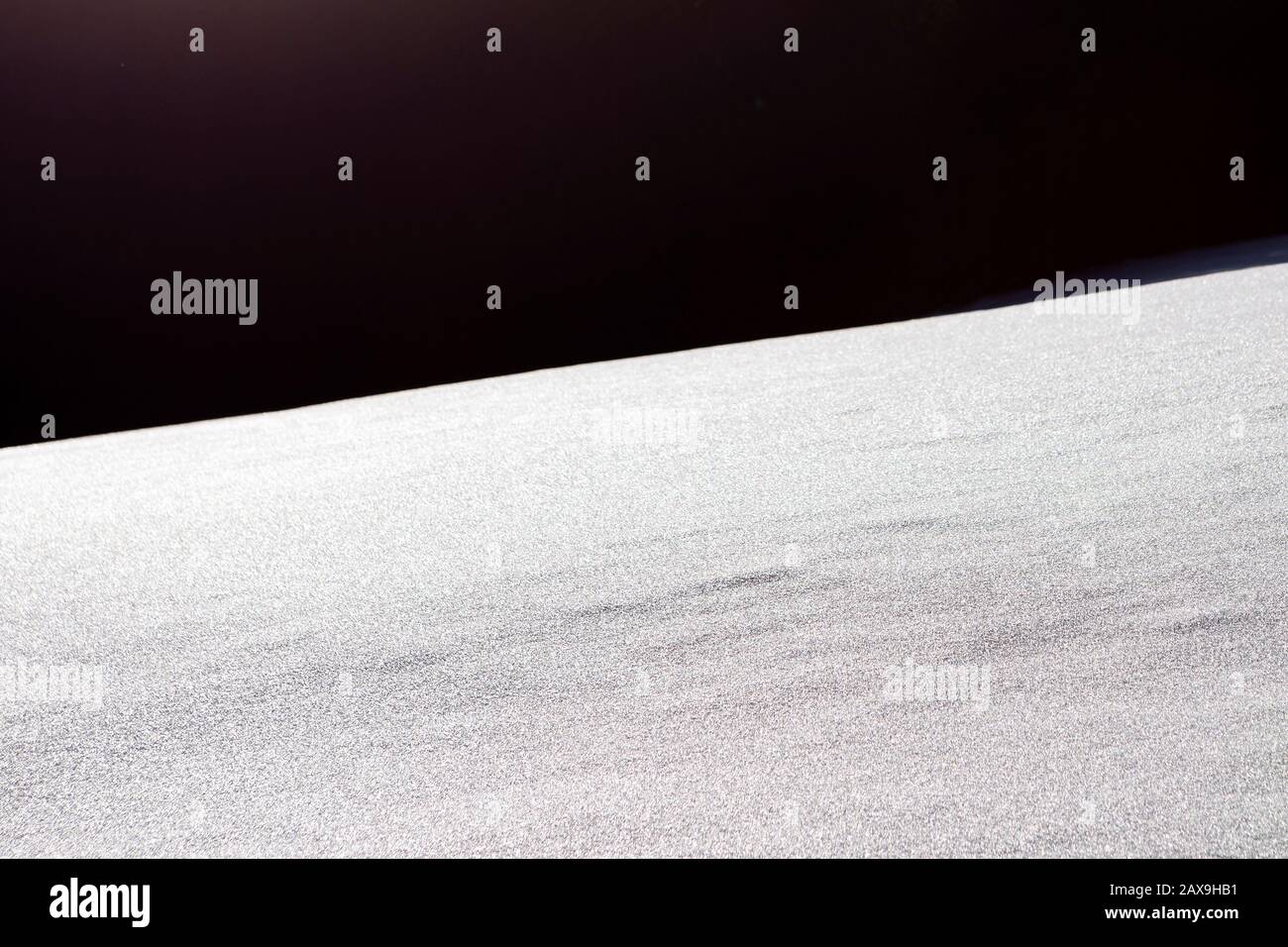 Snowy slope with textured surface with black background. Snow-covered ...