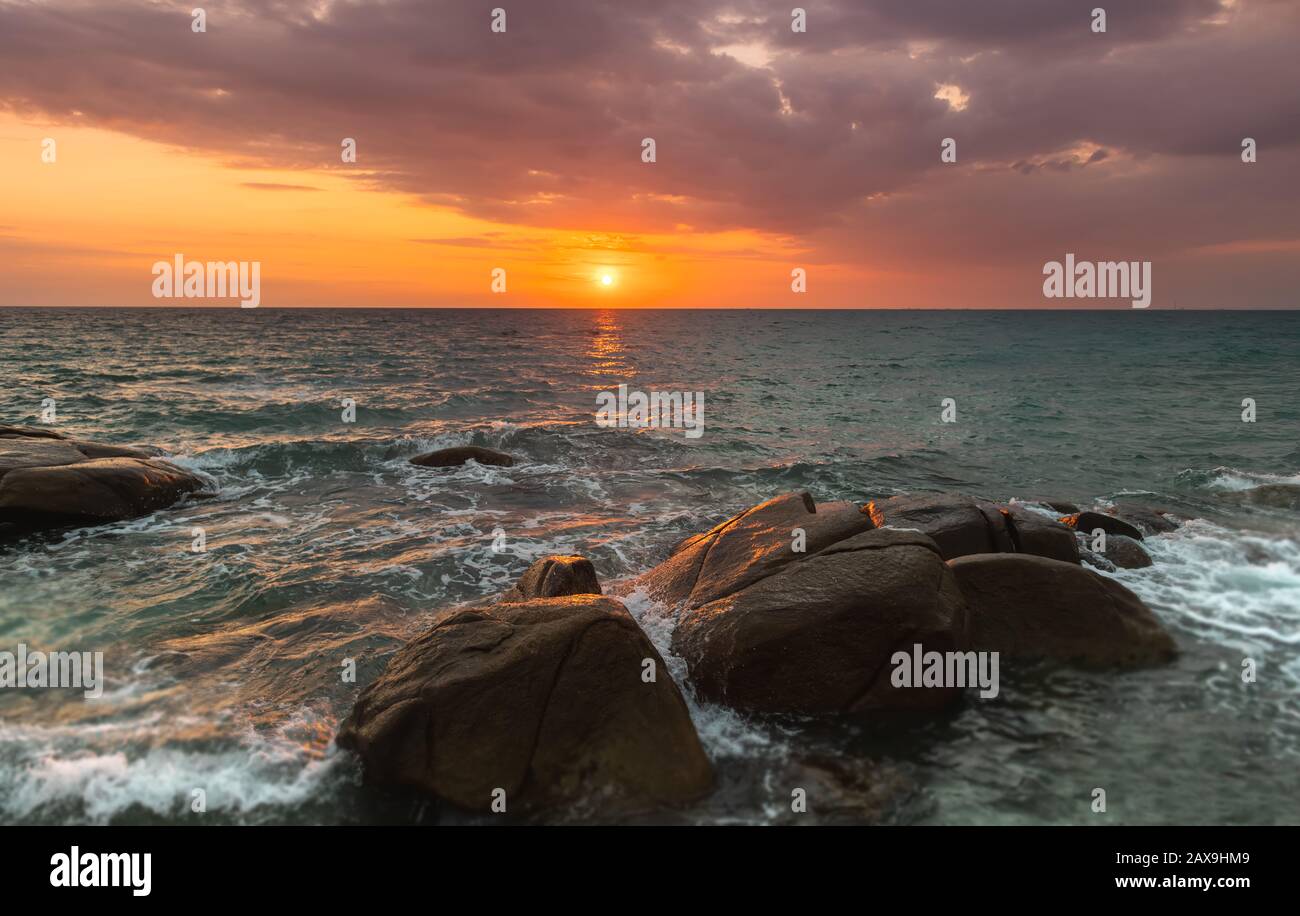Sea scape of sky sun sea and rocks with sunset warm lighting and dark ...