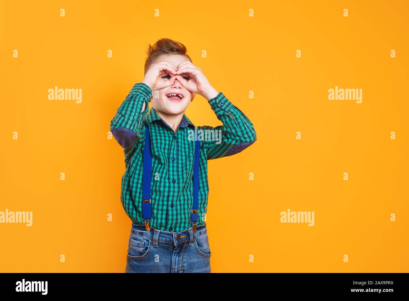 Little boy smiling doing ok sign with hands on eyes looking through ...