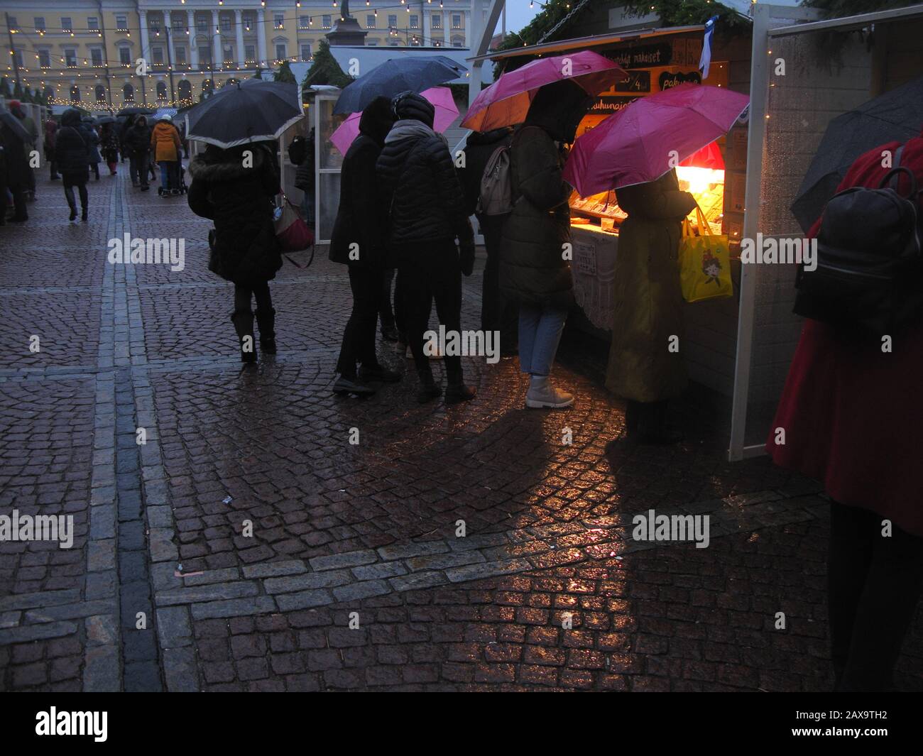 Christmas market visitors in the rain in Helsinki in a pool of warm ...