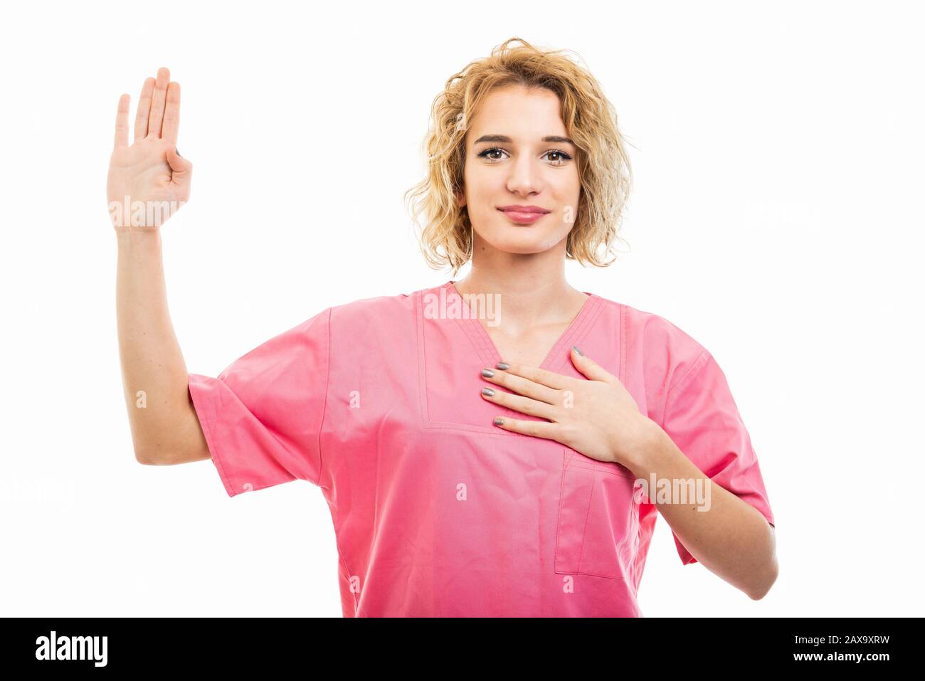 Portrait Of Young Nurse Wearing Pink Scrub Making Oath Gesture Isolated