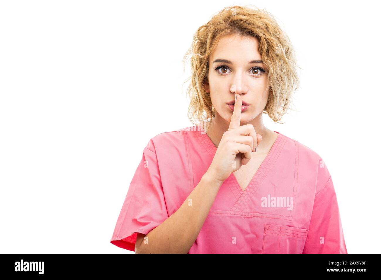 Portrait of nurse wearing pink scrub making silence gesture isolated on ...