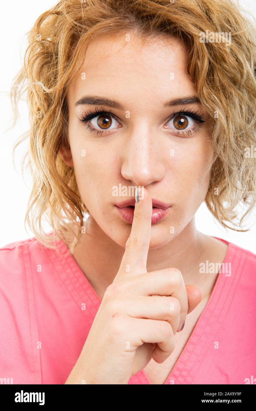 Close-up of nurse wearing pink scrub making silence gesture isolated on ...