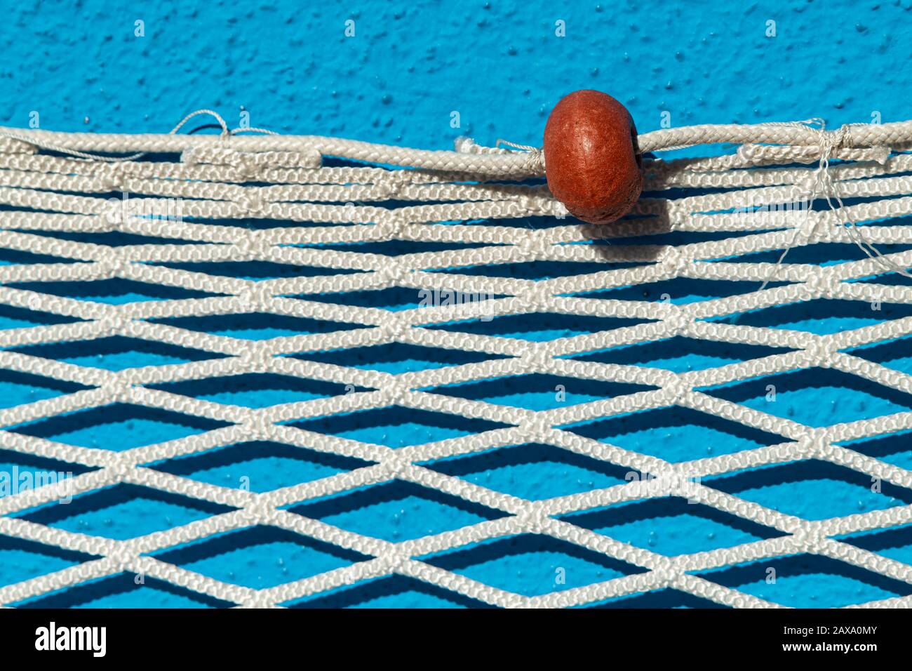 Closeup of a white fisher net hanging on a blue wall Stock Photo - Alamy