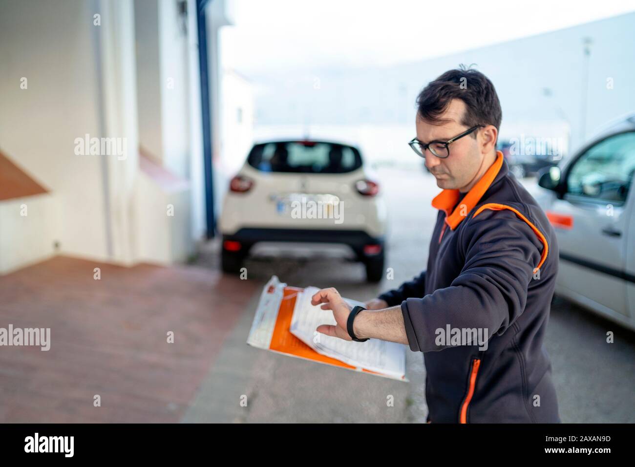 Delivery man with a small orange parcel looking on the watch Stock ...