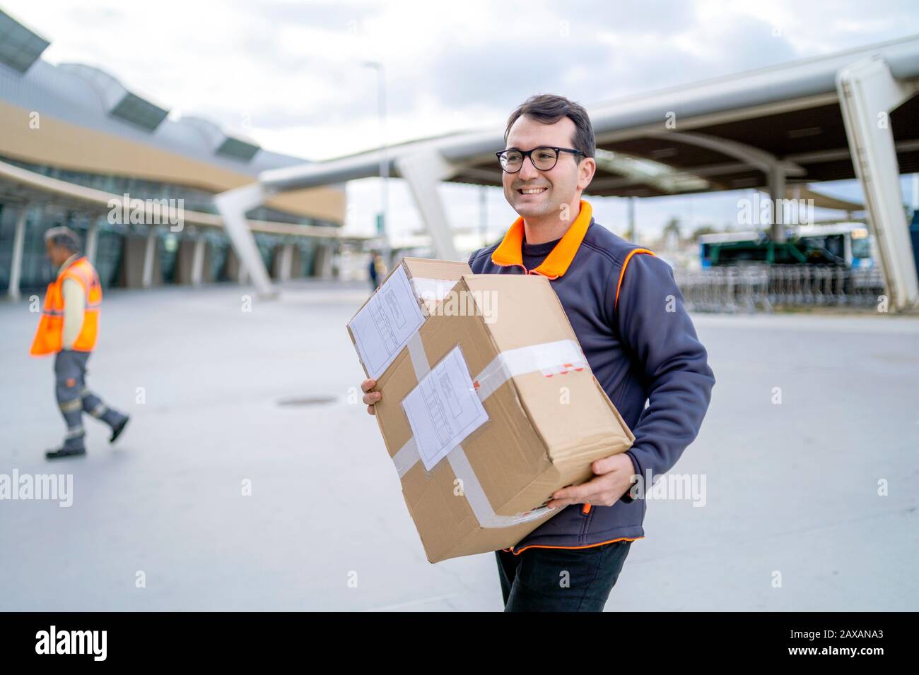 Happy courier with a parcel delivering to a business area Stock Photo ...