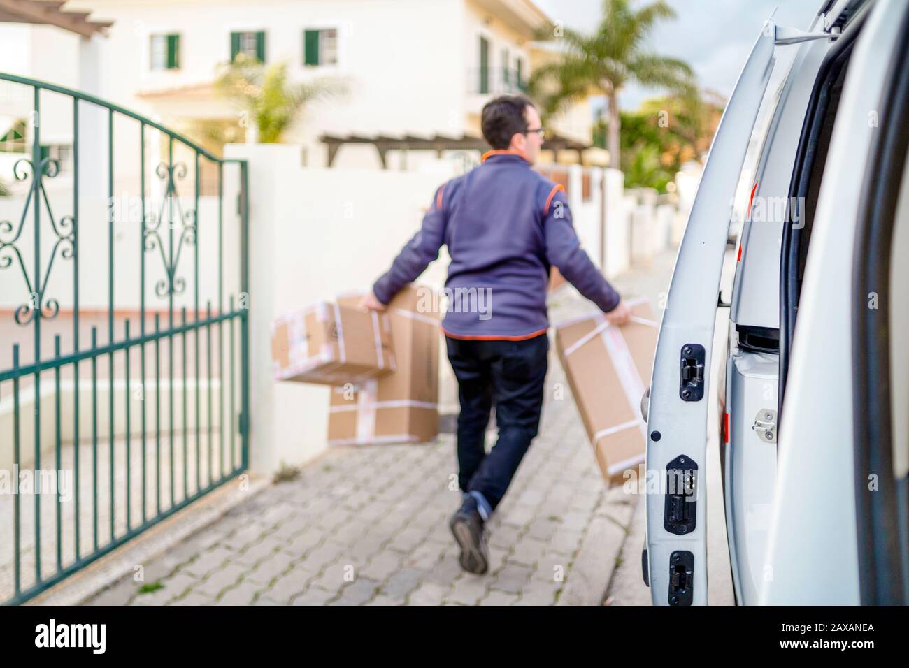 Delivery man carrying a few parcels out of his white car Stock Photo ...