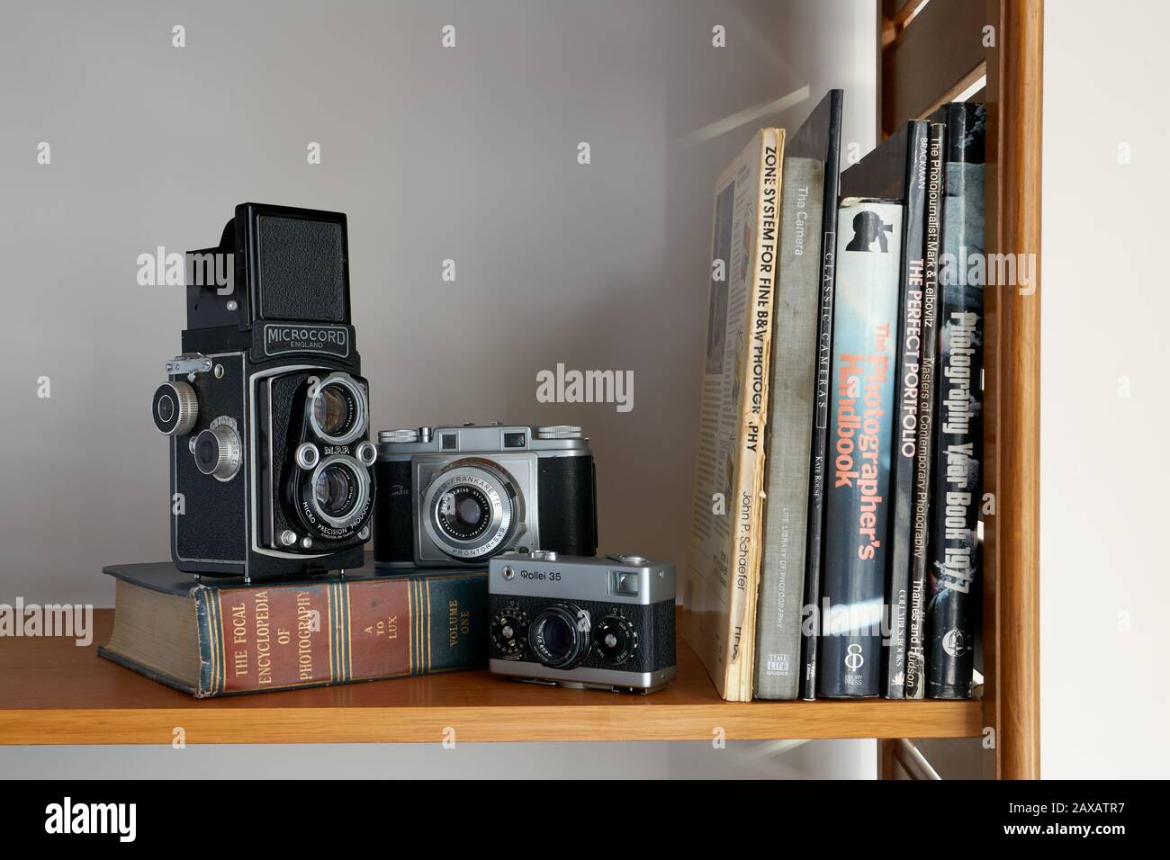 A photograph of three vintage cameras and photography books placed on a ...