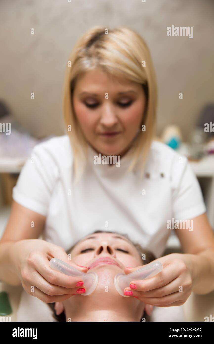 Closeup of cup applied to facial skin of a female patient as part of ...
