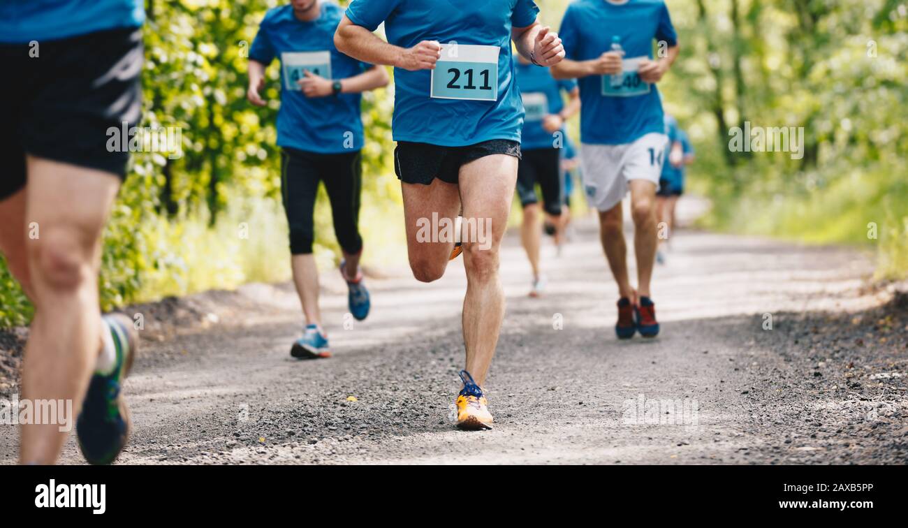 Group of runners running fast through the forest on trail marathon run ...