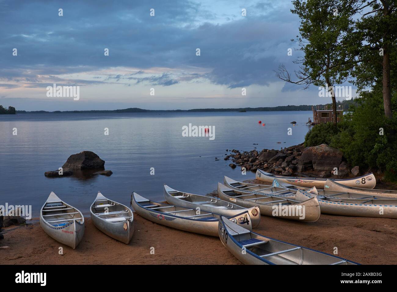 Beached canoe's and kayaks on the shore of Lake Möckeln, Sweden at dusk ...