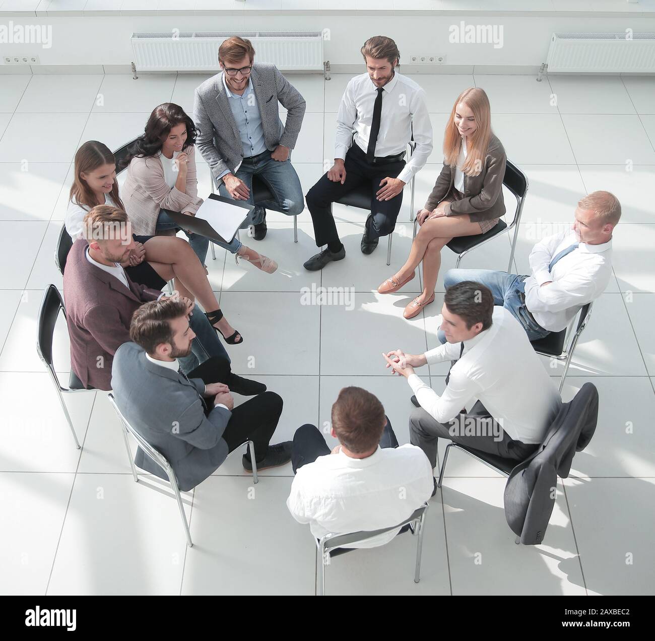 business training participants sitting in a circle and looking at the ...