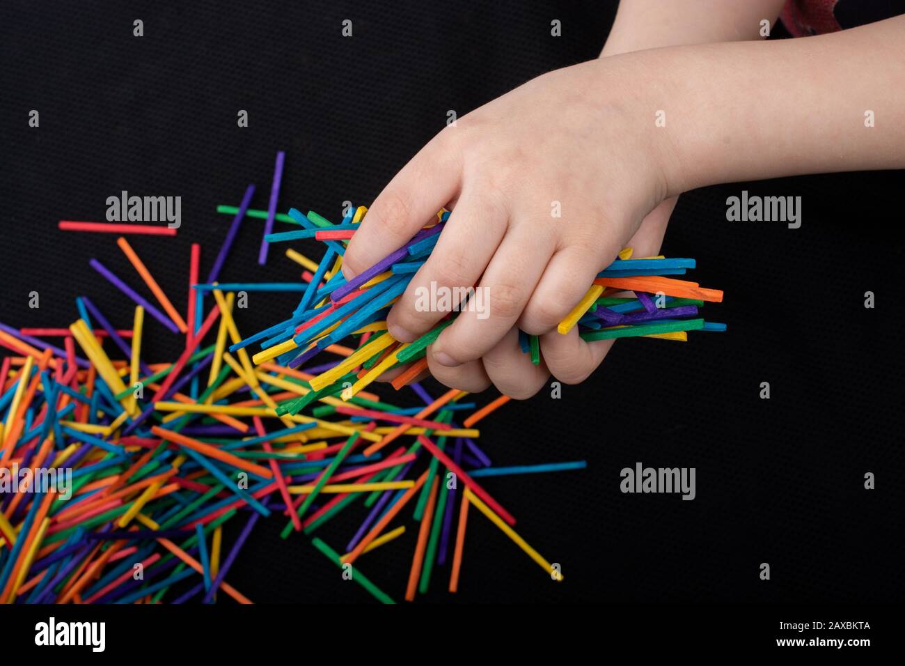 Kid playing with coloured wooden sticks for creativity on white ...