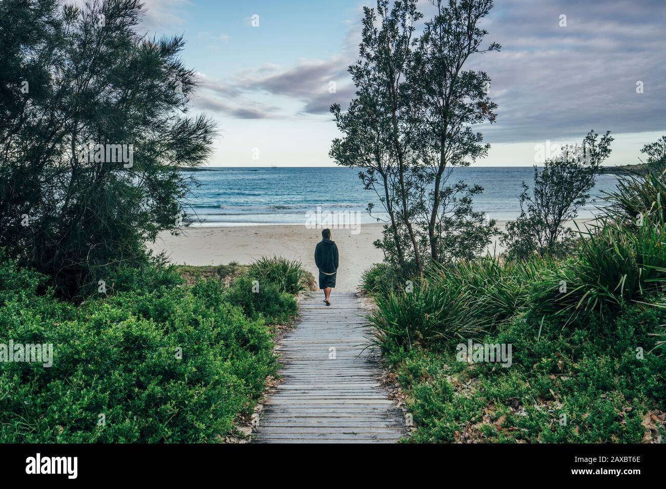 Man walking on footpath toward idyllic ocean beach Kiola Australia ...
