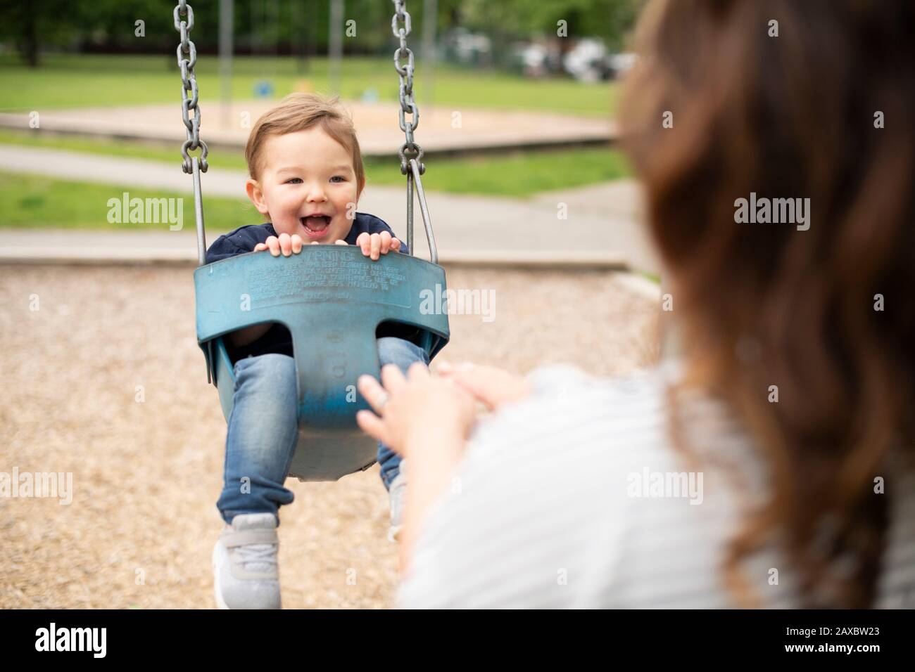 Mother pushing happy cute toddler girl in swing at playground Stock ...