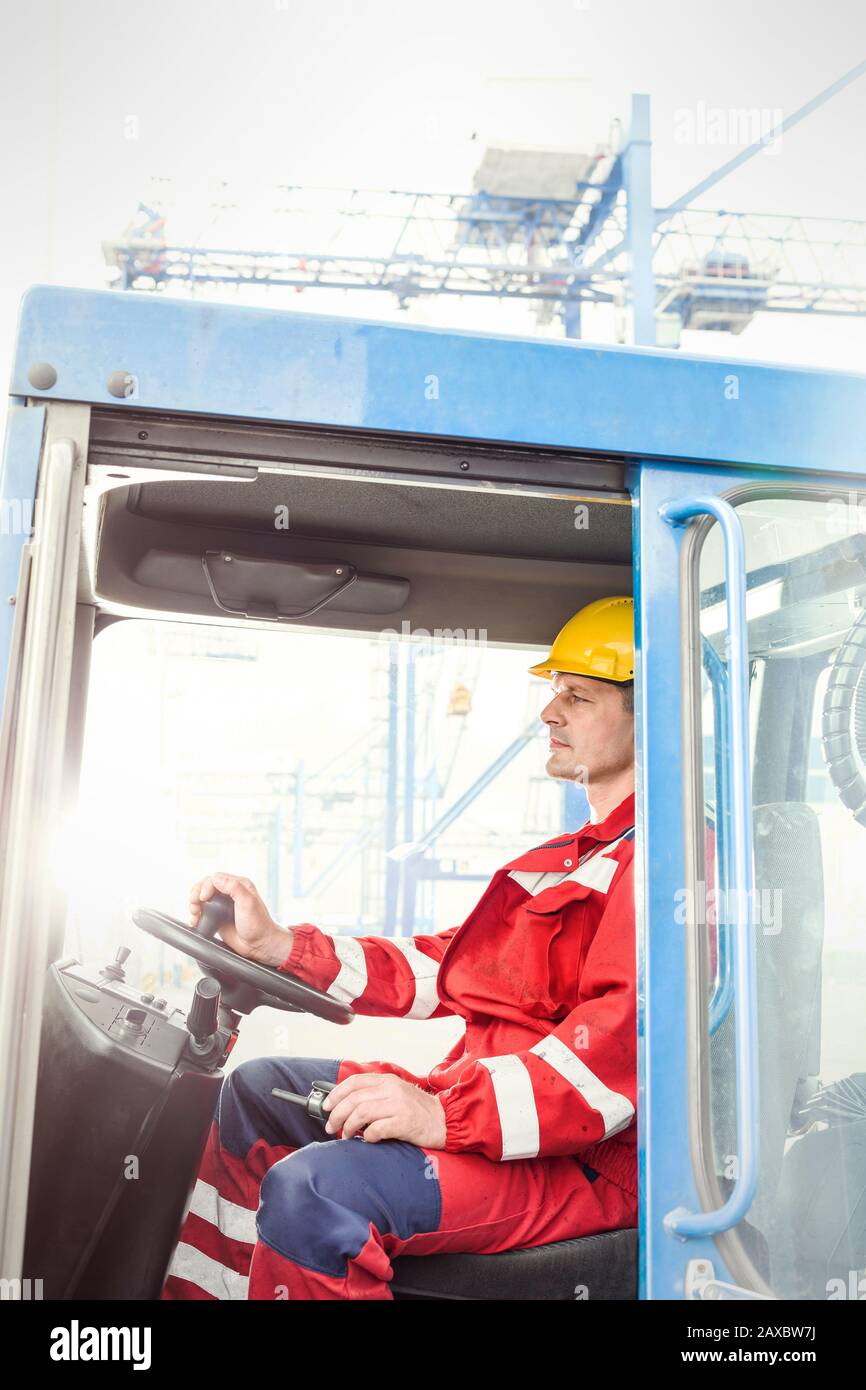 Dock worker driving forklift at shipyard Stock Photo - Alamy
