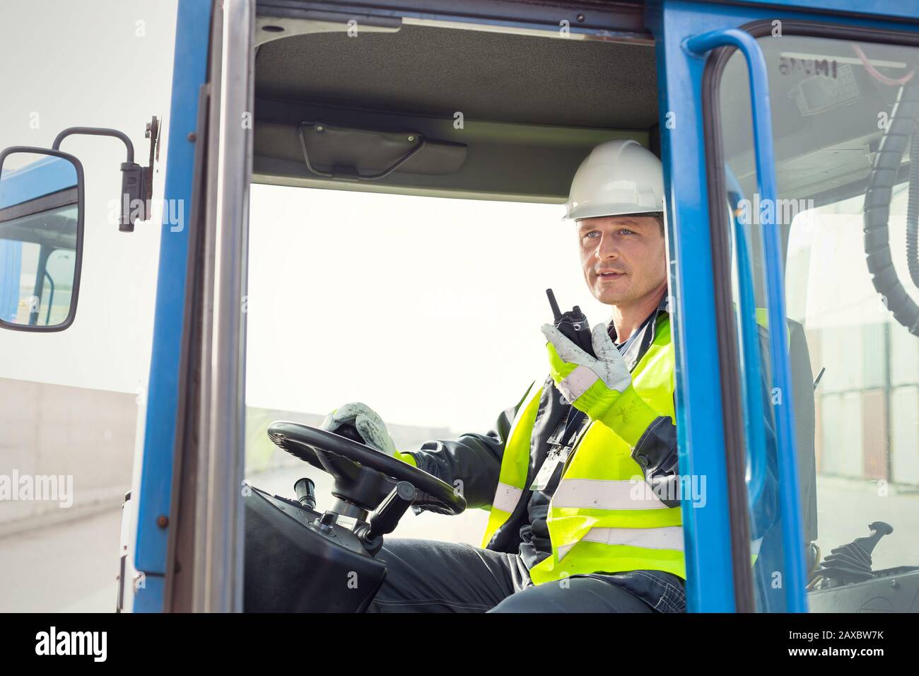 Dock worker using walkie-talkie and operating crane at shipyard Stock ...