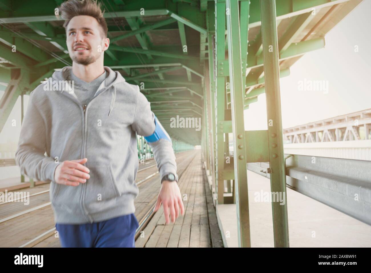 Young male runner running along urban train tracks Stock Photo - Alamy