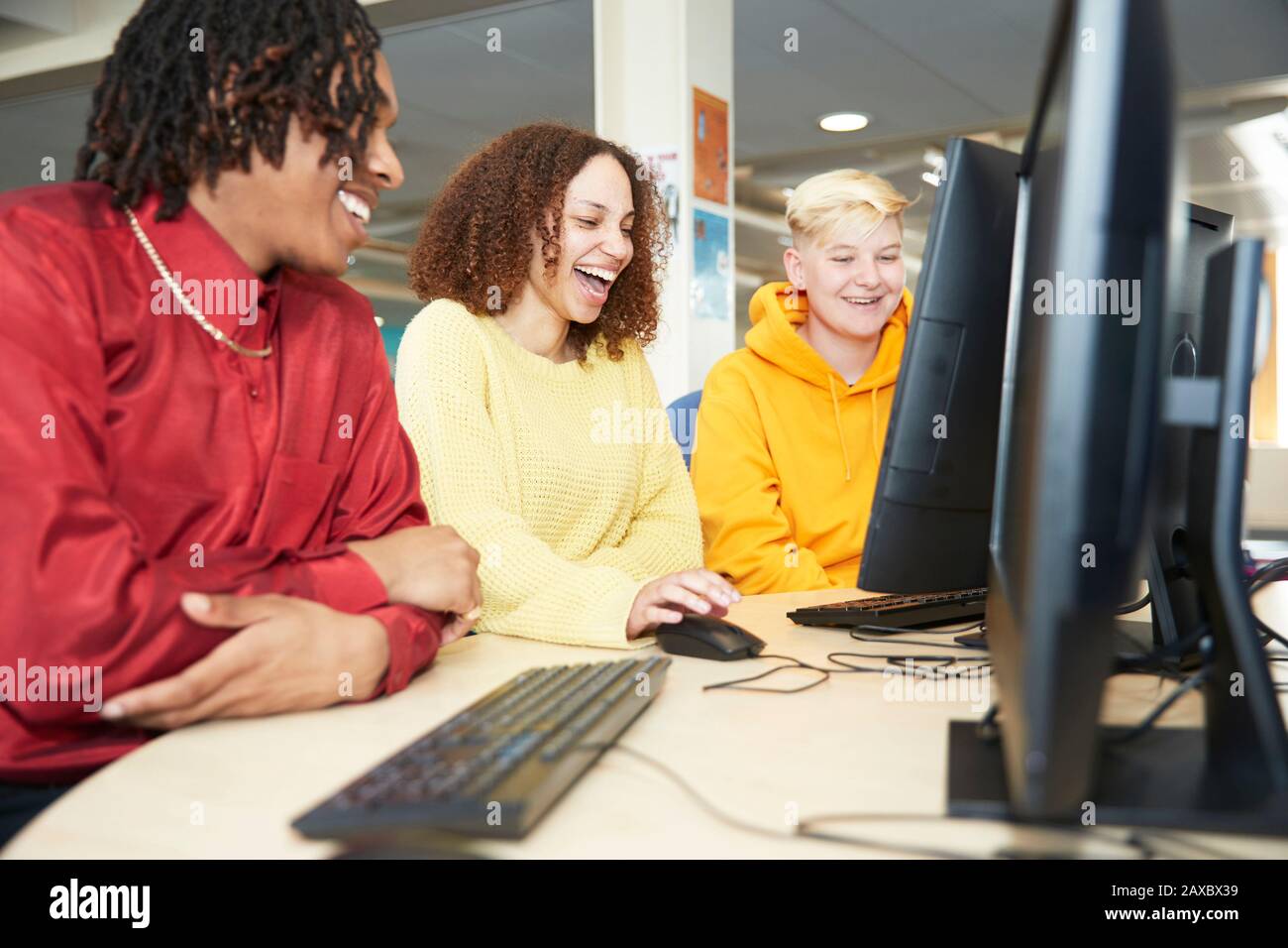 Happy college students studying together at computer in library Stock ...