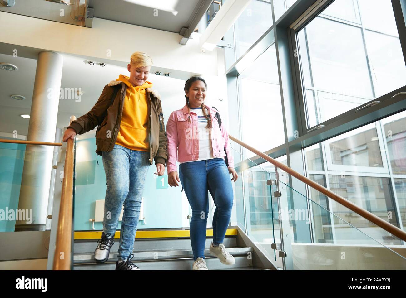 Confident young female college students descending staircase Stock ...