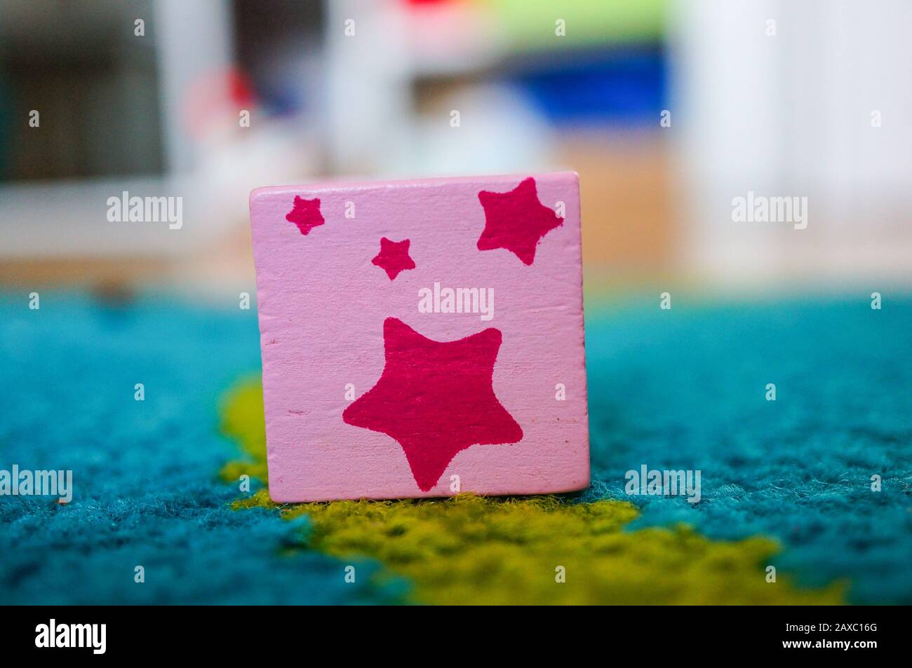 Pink square toy with stars on its surface put on a multicolored surface ...