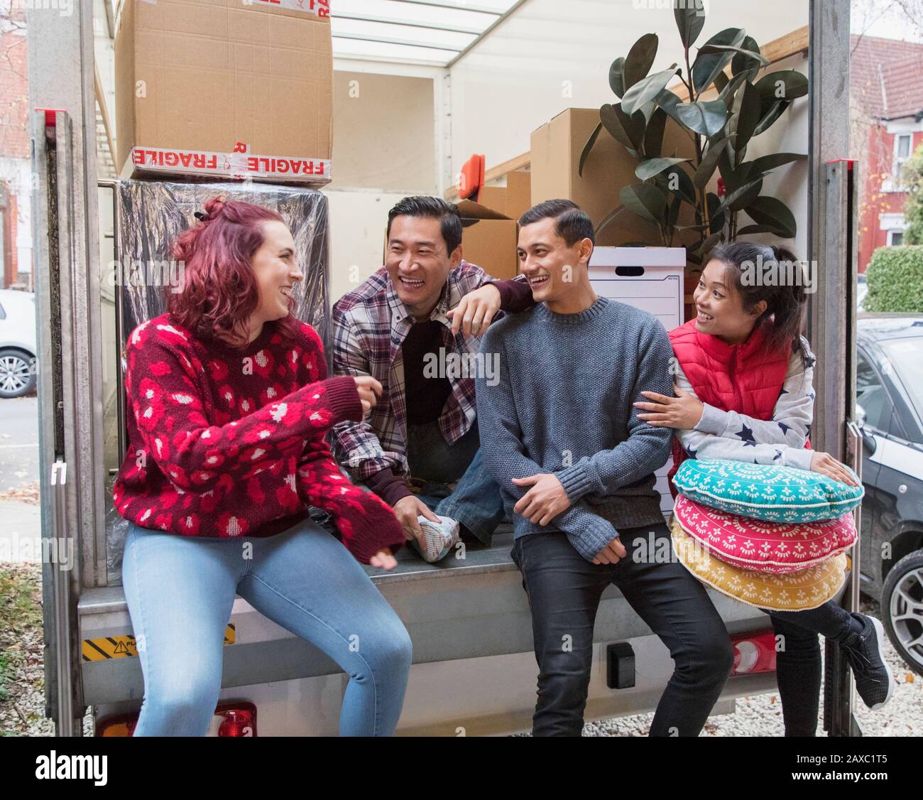 Happy friends talking at back of moving van Stock Photo - Alamy