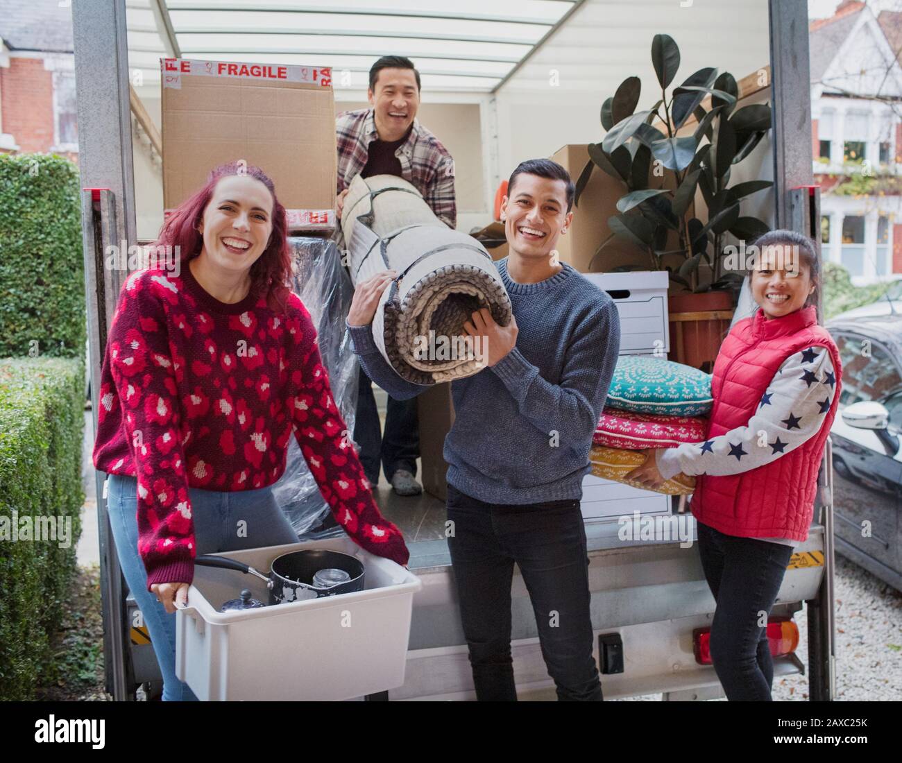 Portrait happy friends unloading moving van in driveway Stock Photo - Alamy