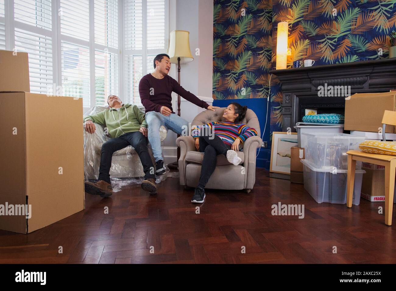 Friends taking a break from moving, relaxing in living room Stock Photo ...