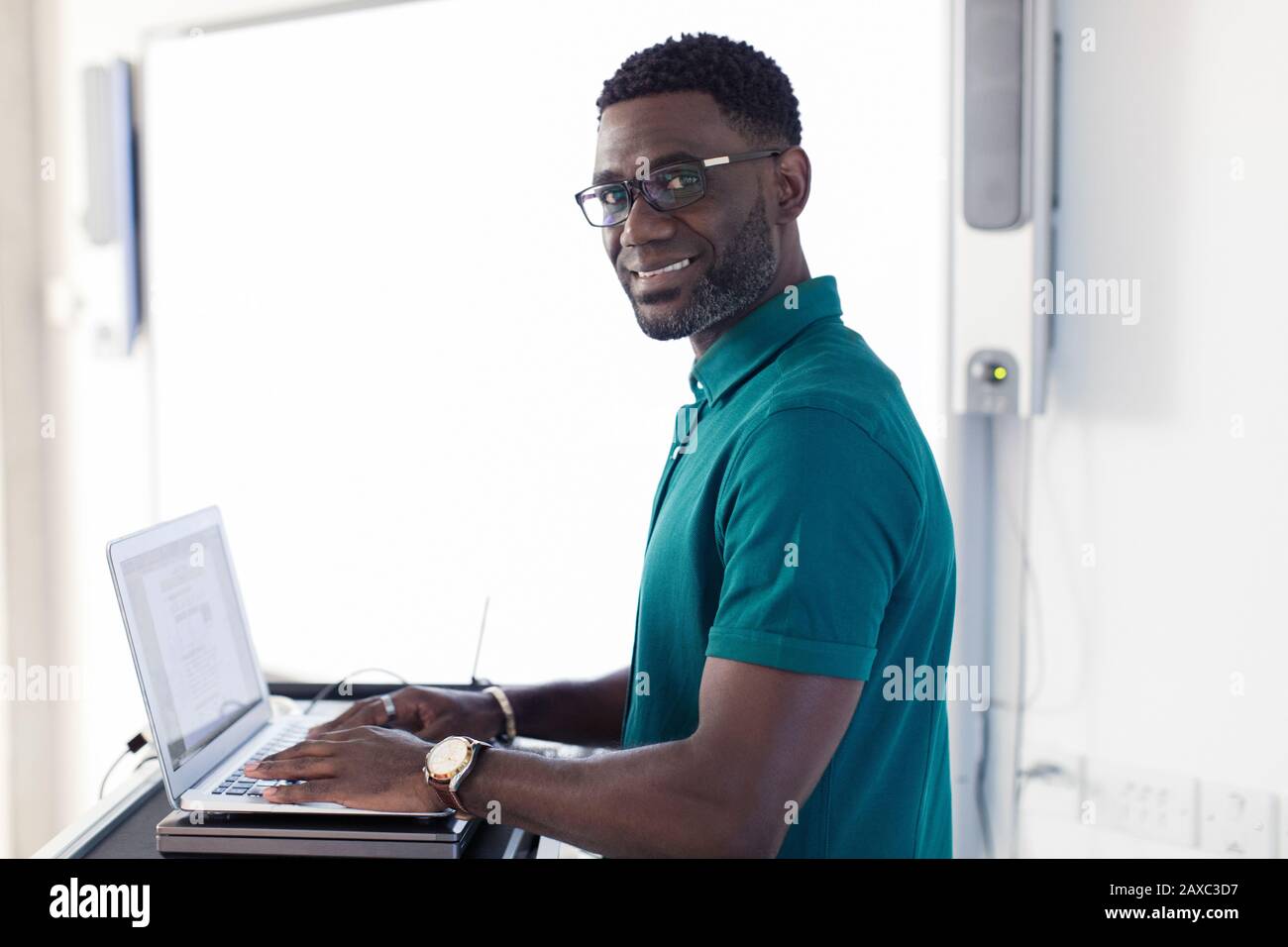 Portrait smiling, confident male instructor at laptop preparing in ...
