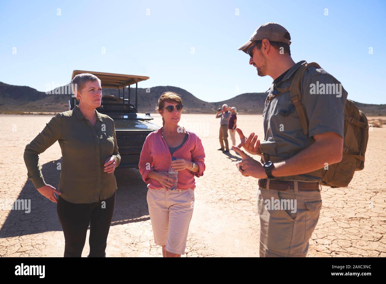Safari tour guide talking with women in sunny desert South Africa Stock ...