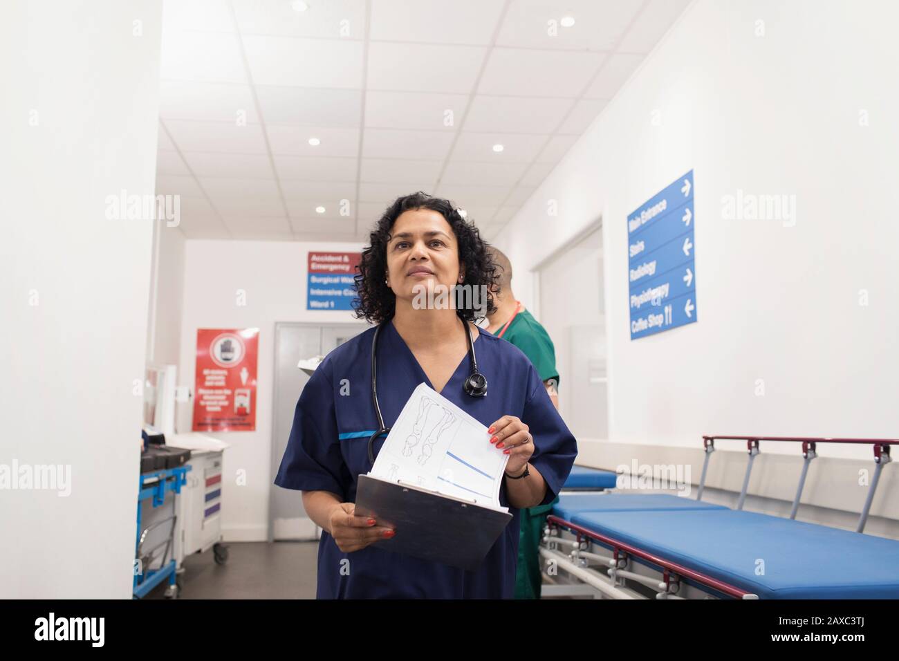 Confident female doctor with medical chart making rounds in hospital ...