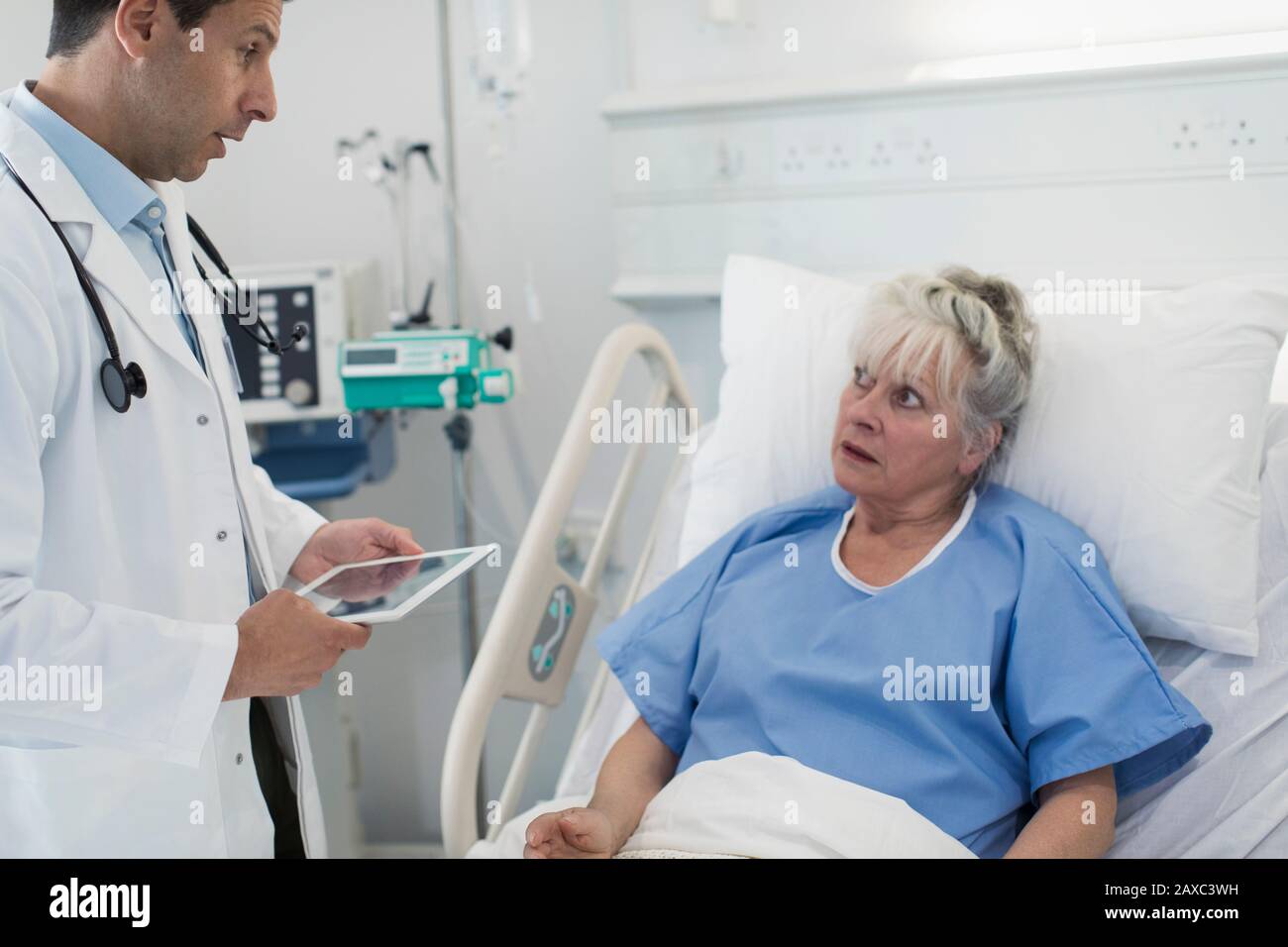 Doctor with digital tablet making rounds, talking with senior patient ...