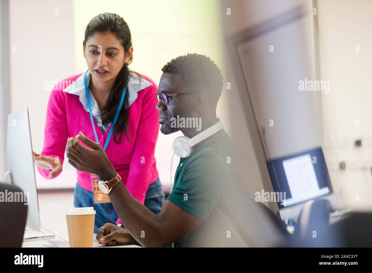 Community college instructor helping student at computer in computer ...