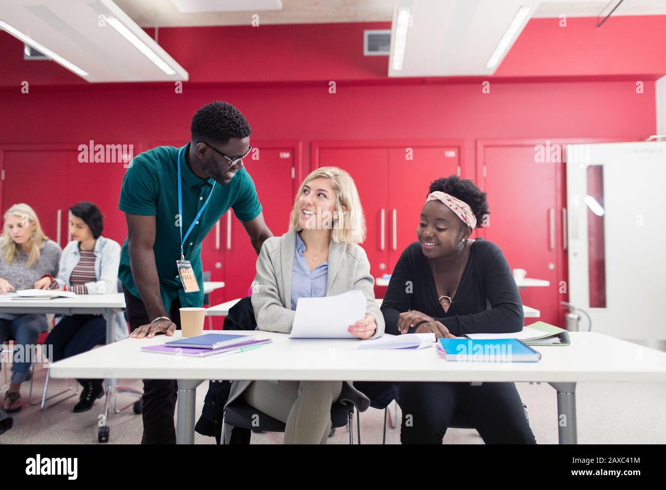 Community college instructor helping students with paperwork in ...