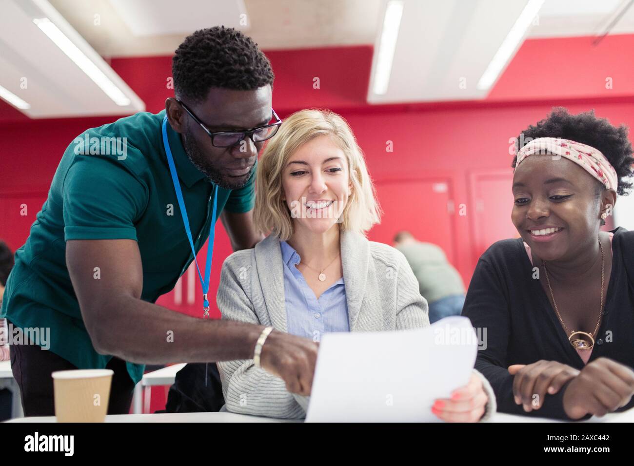Community college instructor helping students with paperwork in ...