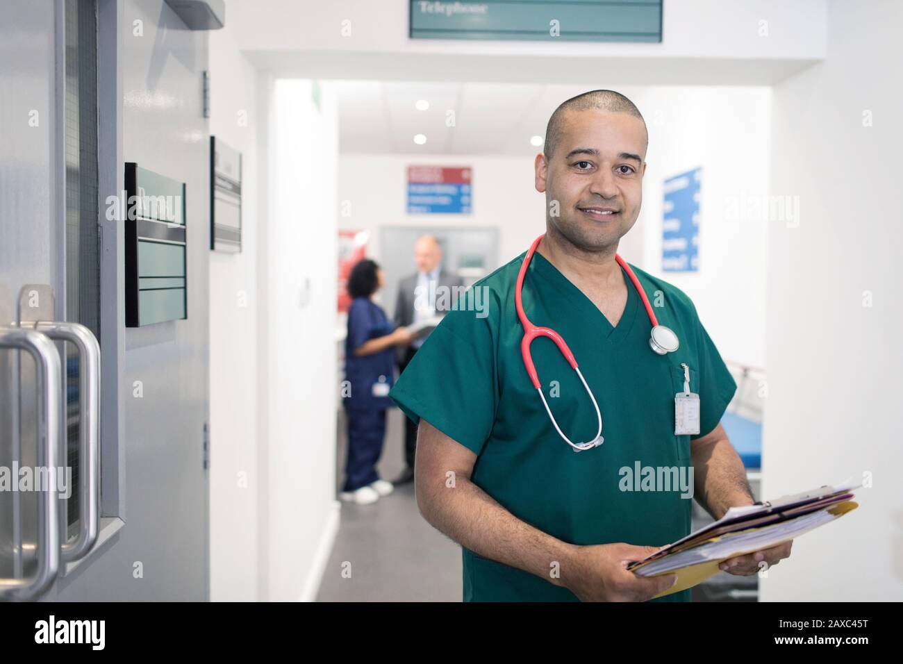 Portrait confident male doctor with medical chart making rounds in ...