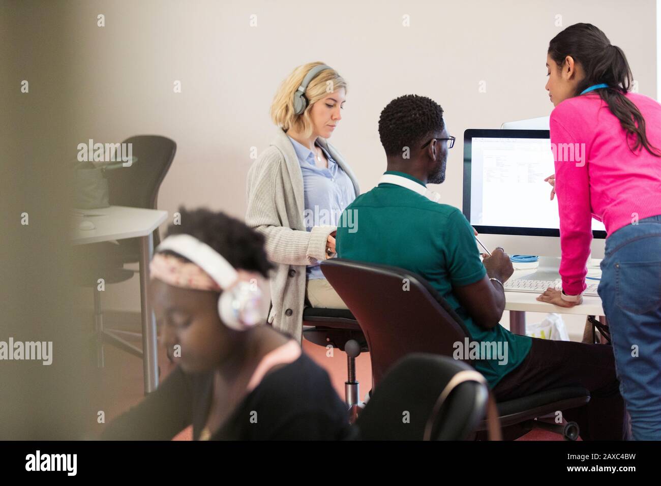 Community college instructor helping students at computers in computer ...