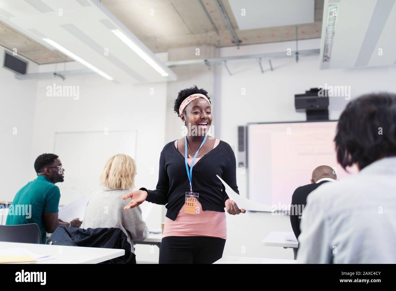 Smiling female community college instructor leading lesson in classroom ...