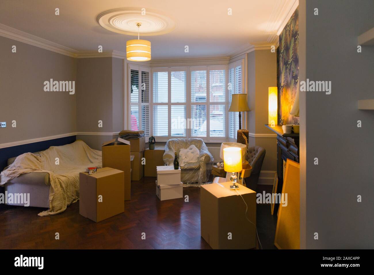 Moving boxes in illuminated living room Stock Photo - Alamy