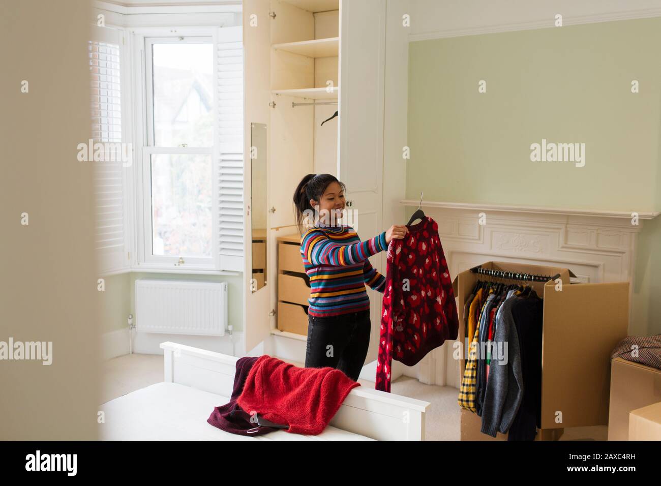 Woman unpacking clothing from moving box in bedroom Stock Photo - Alamy