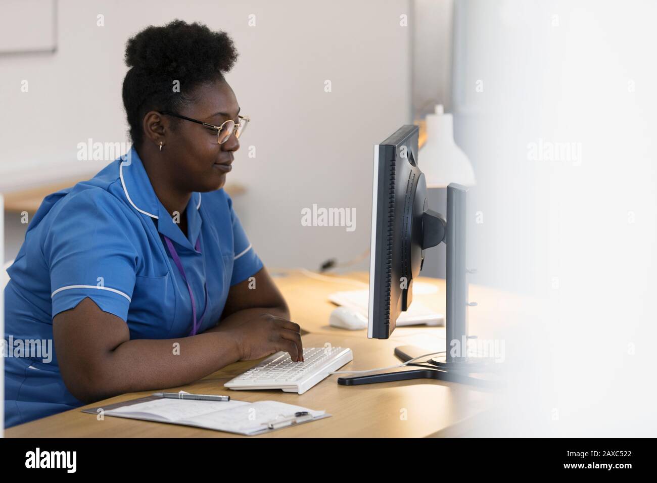 Female nurse working at computer in doctors office Stock Photo - Alamy