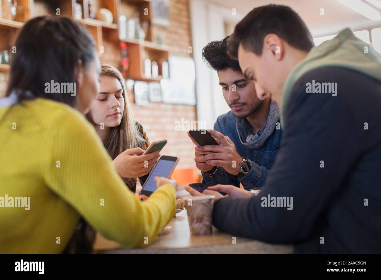 Young adult friends using smart phones at cafe table Stock Photo - Alamy