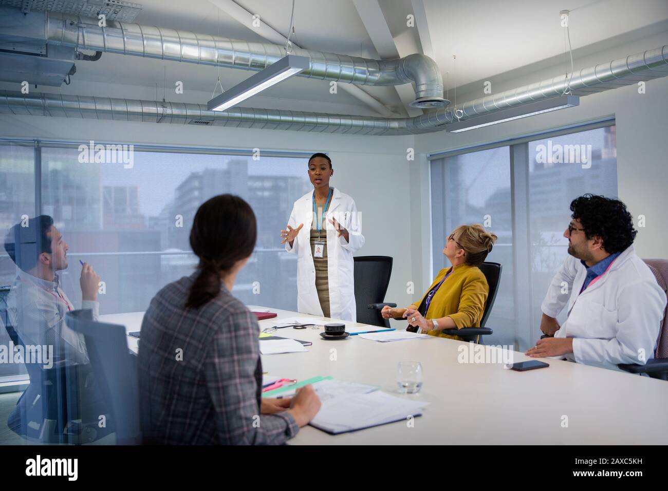 Female doctor leading conference room meeting Stock Photo - Alamy