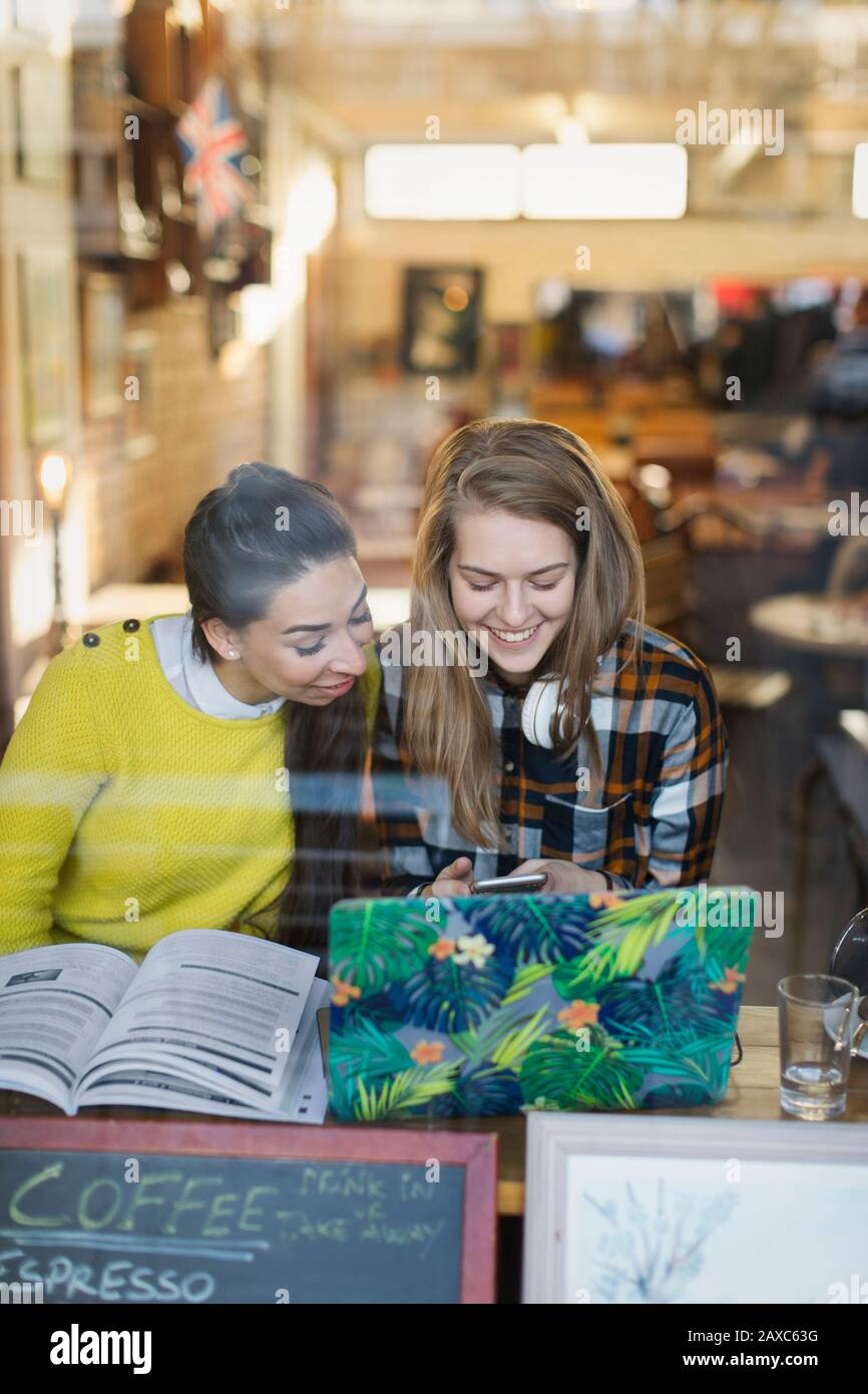 Smiling young female college students studying in cafe Stock Photo - Alamy
