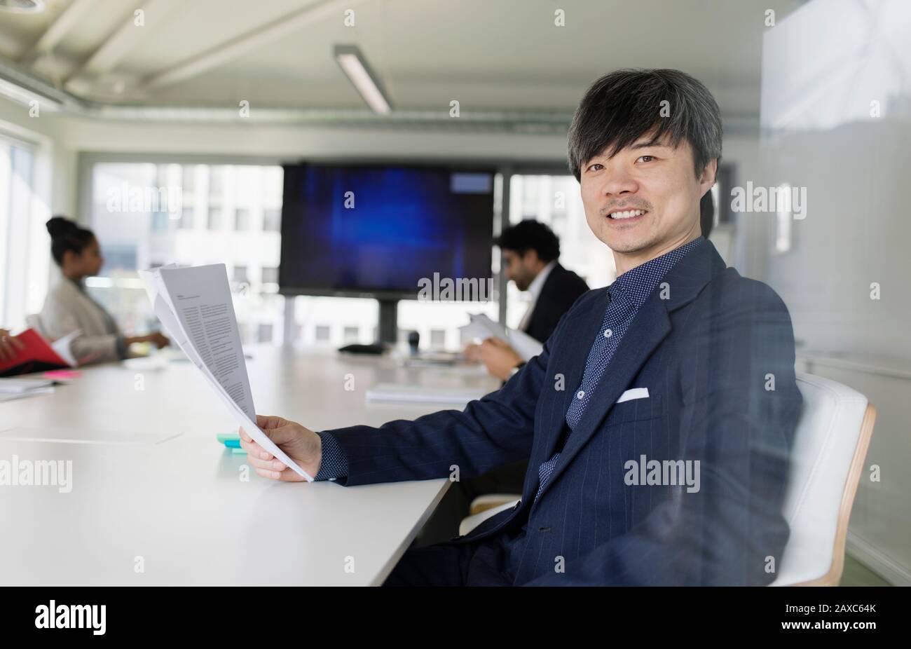 Portrait confident businessman reviewing paperwork in conference room ... Portrait confident businessman reviewing paperwork in conference room ...