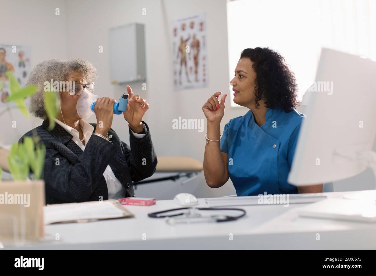 Female doctor teaching senior patient how to use inhaler in doctors ...