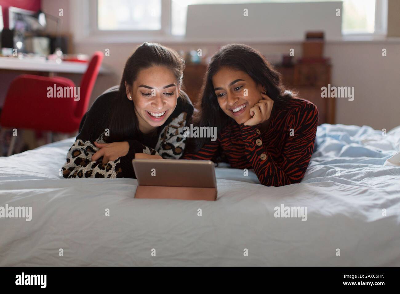 Happy teenage girls using digital tablet on bed Stock Photo - Alamy
