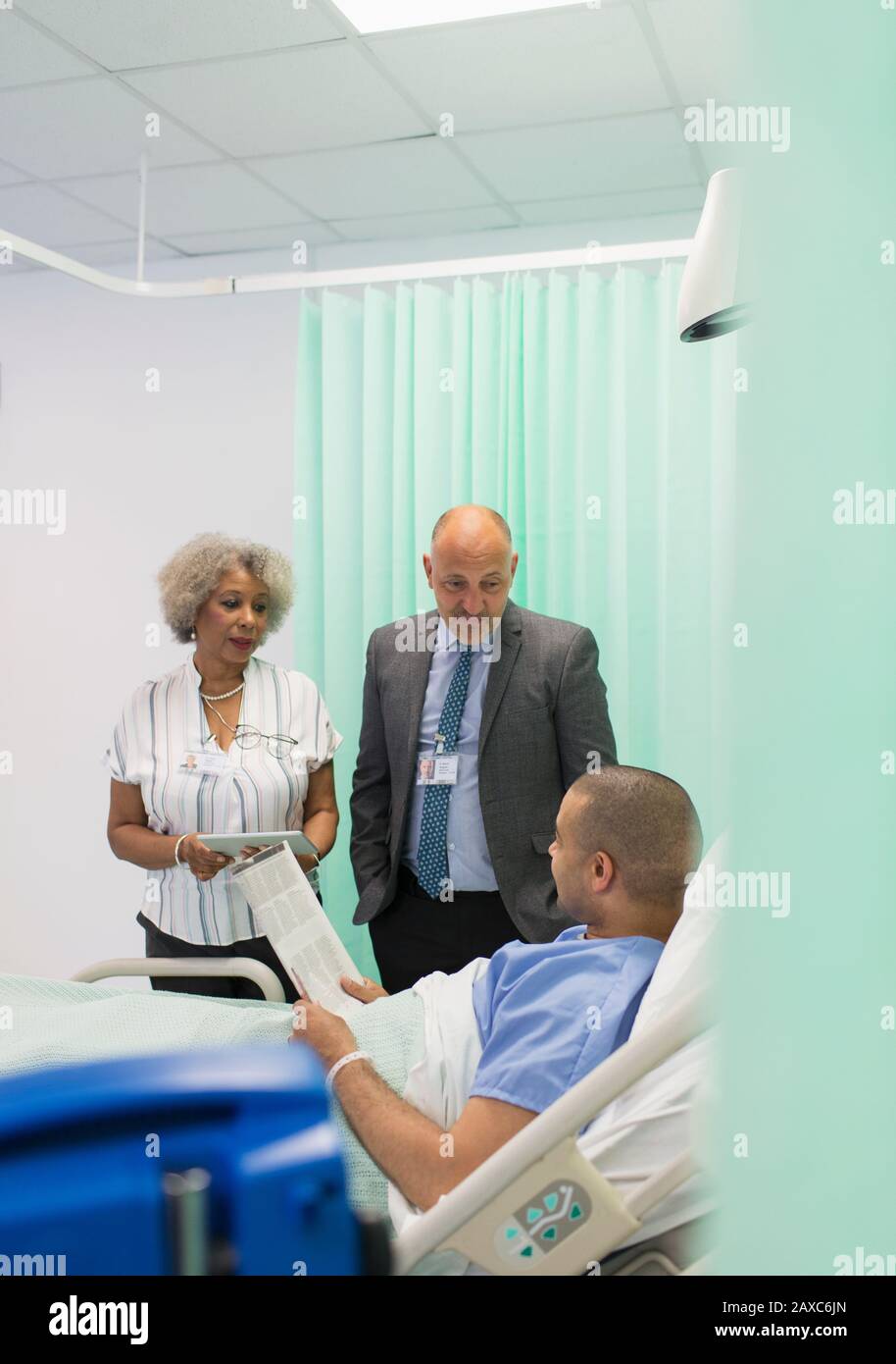 Doctors making rounds, talking with patient in hospital room Stock ...