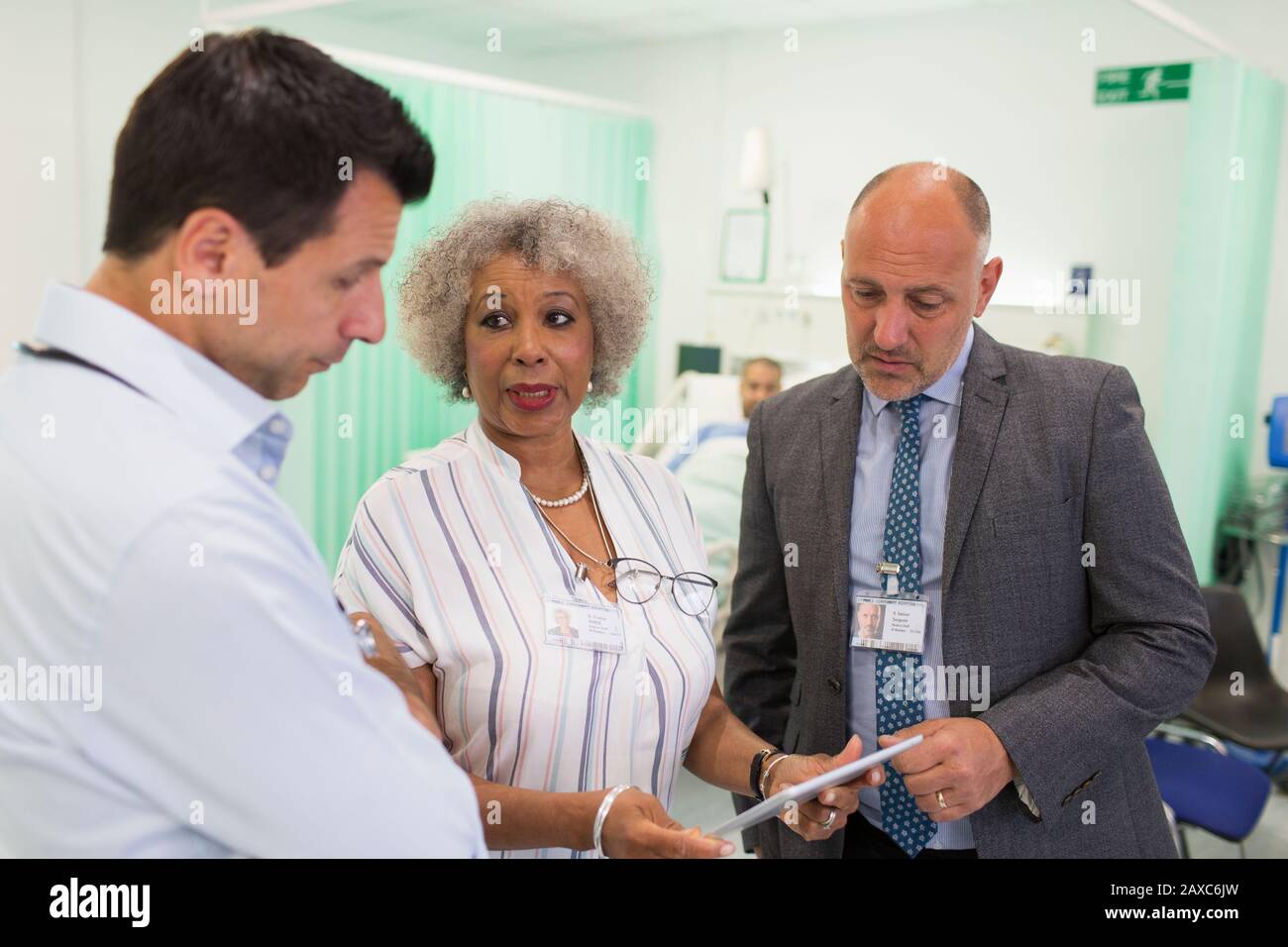 Doctors with digital tablet making rounds, consulting in hospital room ...