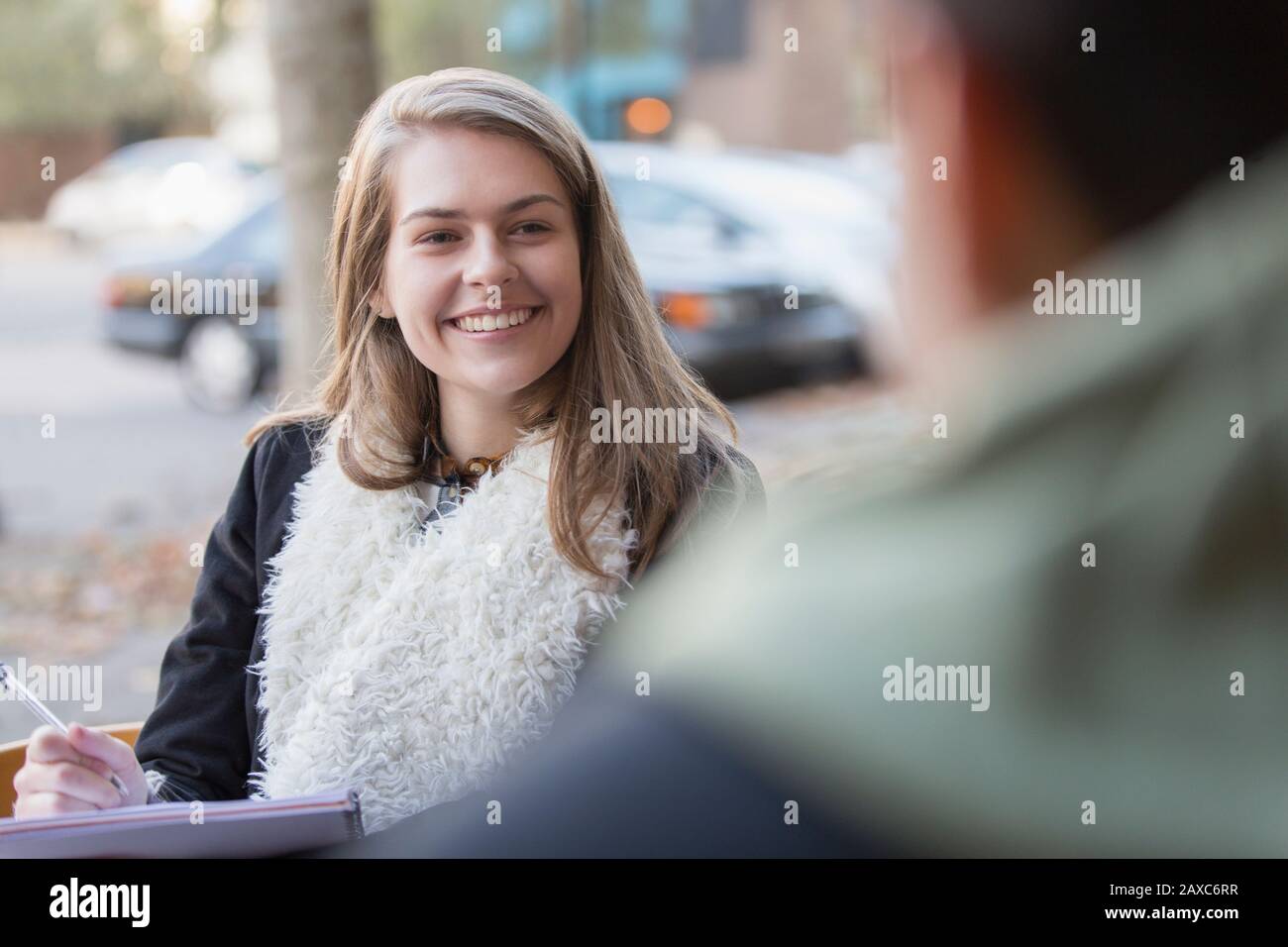 Happy young female college student studying at sidewalk cafe Stock ...